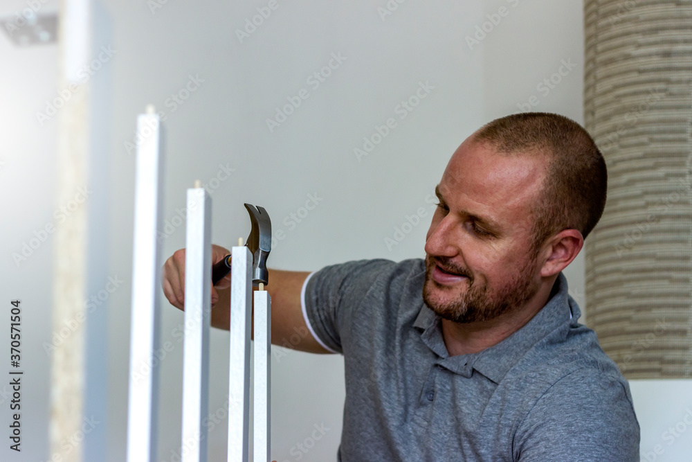 Man assembling furniture at home on the floor. Portrait of a man using ...