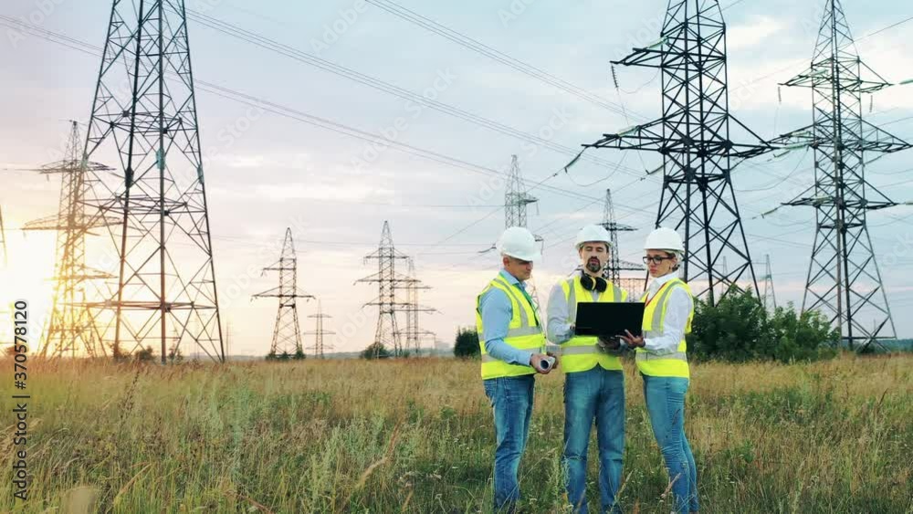 Power engineers are talking near electrical transmission towers Stock ...