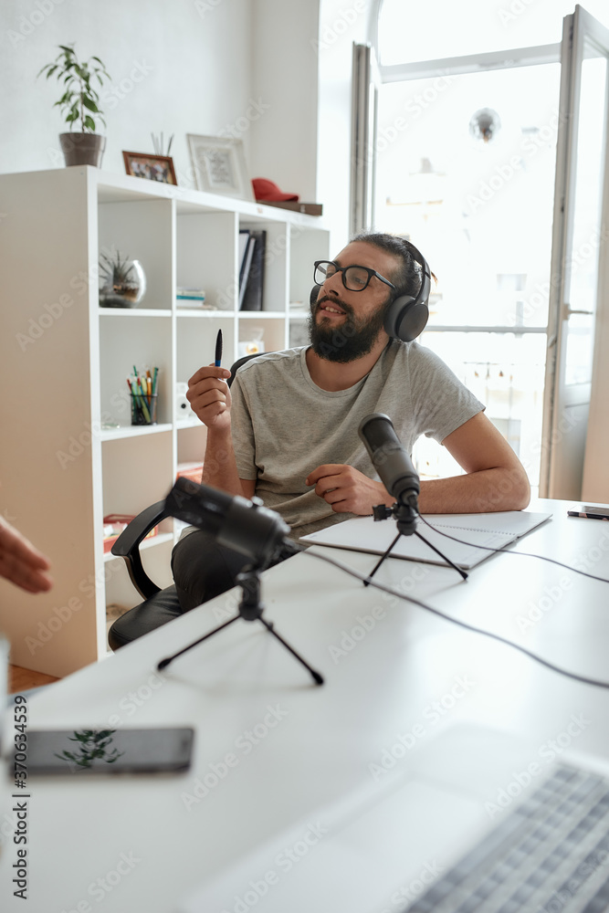 Male blogger, man in headphones listening to interlocutor while talking ...