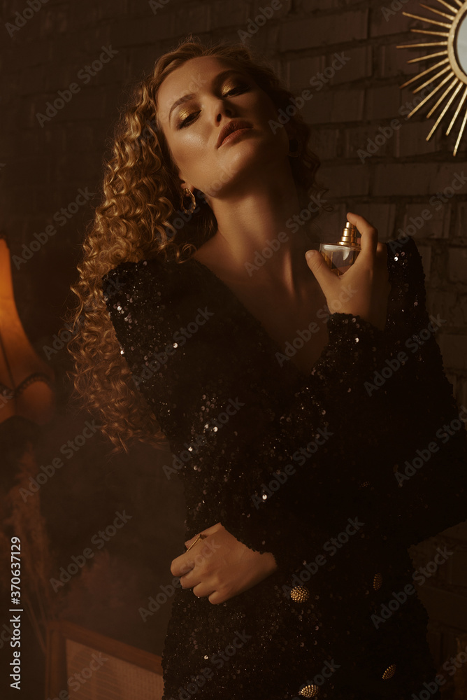 Beautiful woman uses perfume fragrance. Model wearing trendy sequin ...