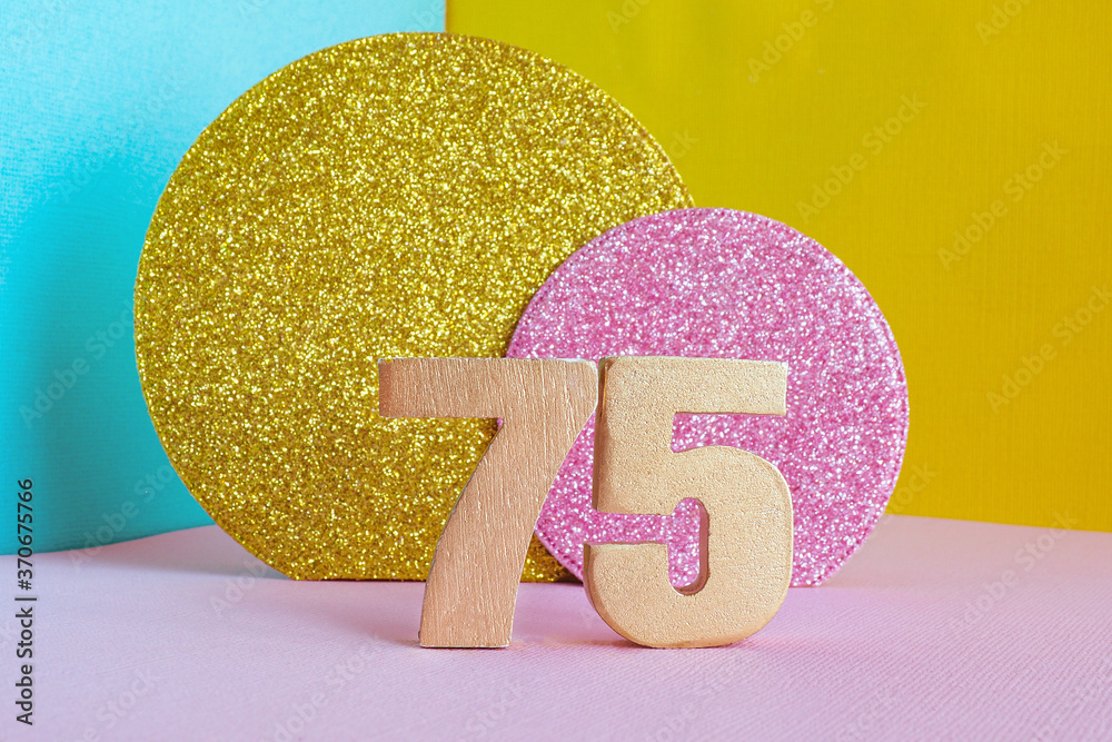the gold number “75” on a multicolored blue-yellow-pink background and ...
