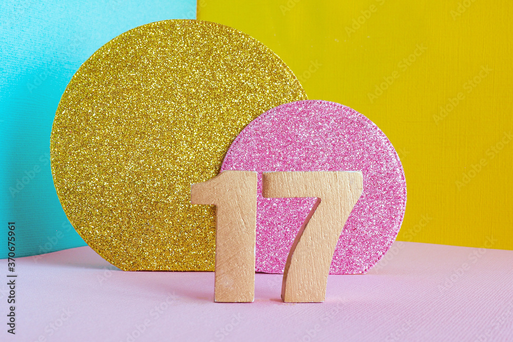 the gold number "17" on a multi-colored blue-yellow-pink background and ...