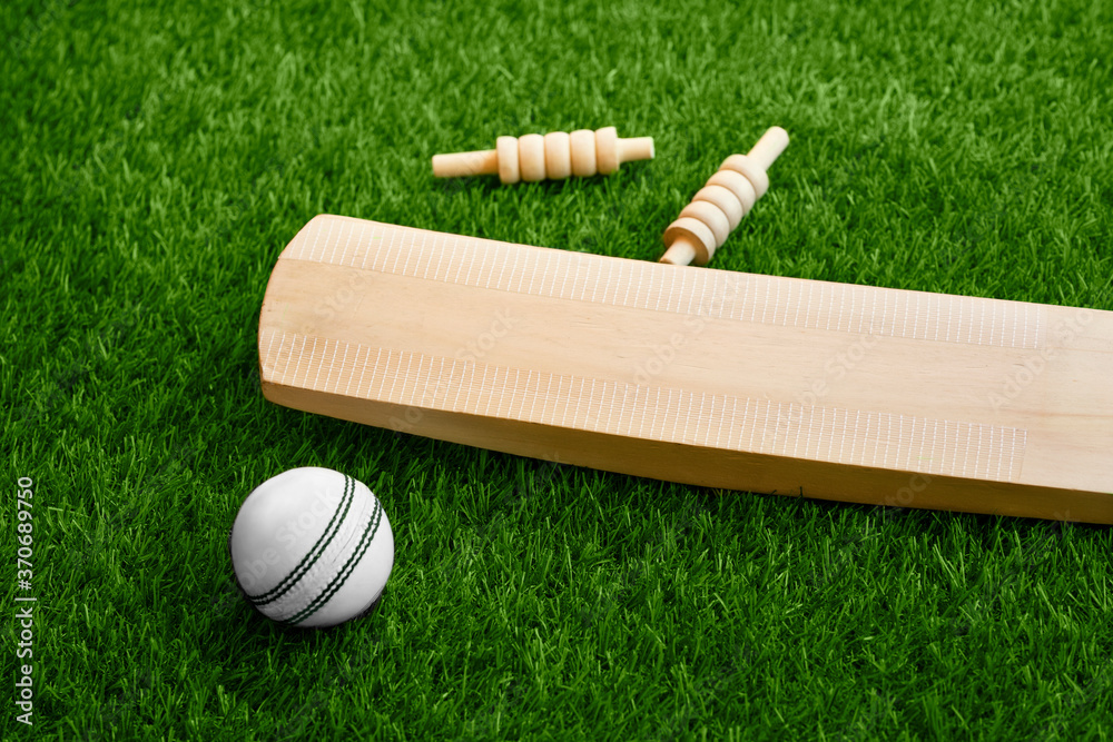 cricket set bat ball stumps and bails on green grass pitch background ...