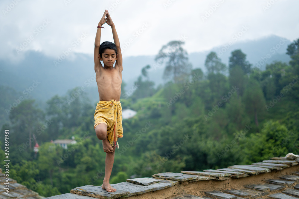 A young indian cute kid doing yoga in the mountains,wearing a dhoti ...