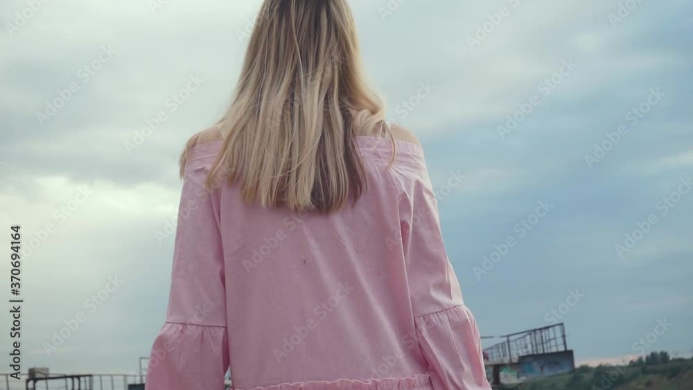 camera shoots from behind girl's back, blonde with long hair appears ...