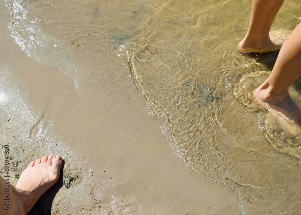 close-up - the legs of a child standing in the shallow water of a river ...