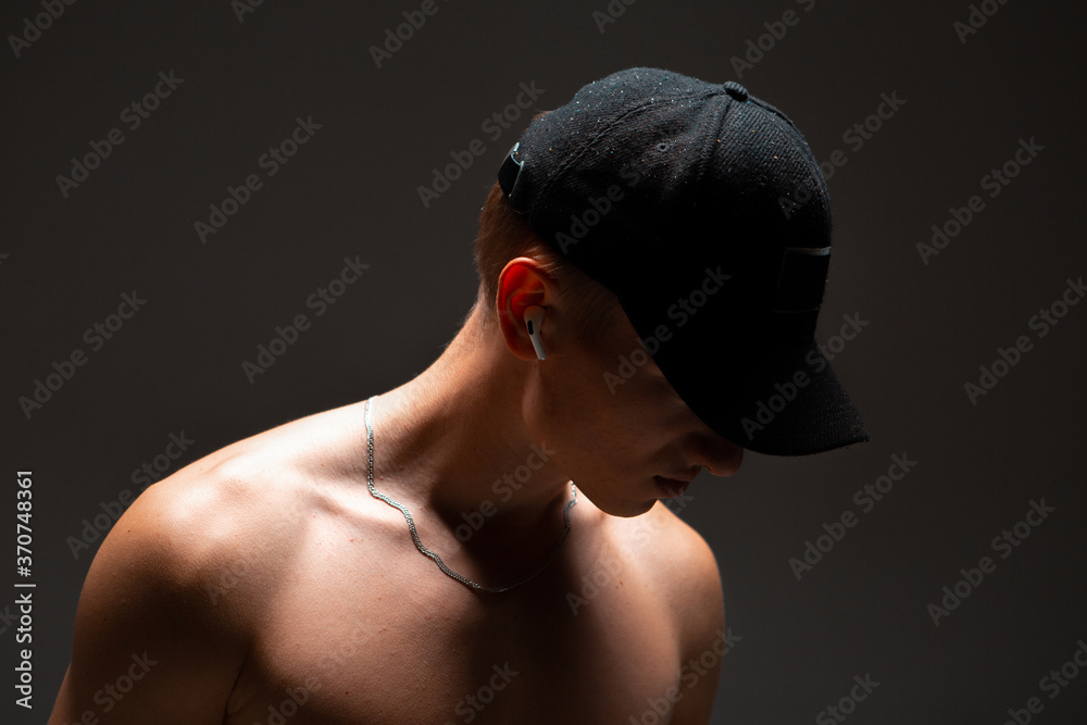 Cool young guy in cap and in a wireless earphone listen to song on ...