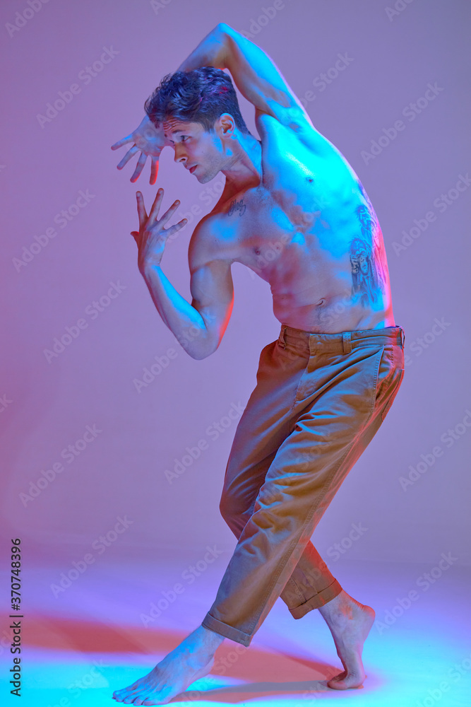 Cool young man dancing expressive dance without shirt in neon light ...