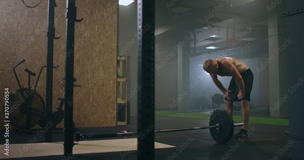 Tired male athlete in the gym rests and prepares to perform an exercise ...