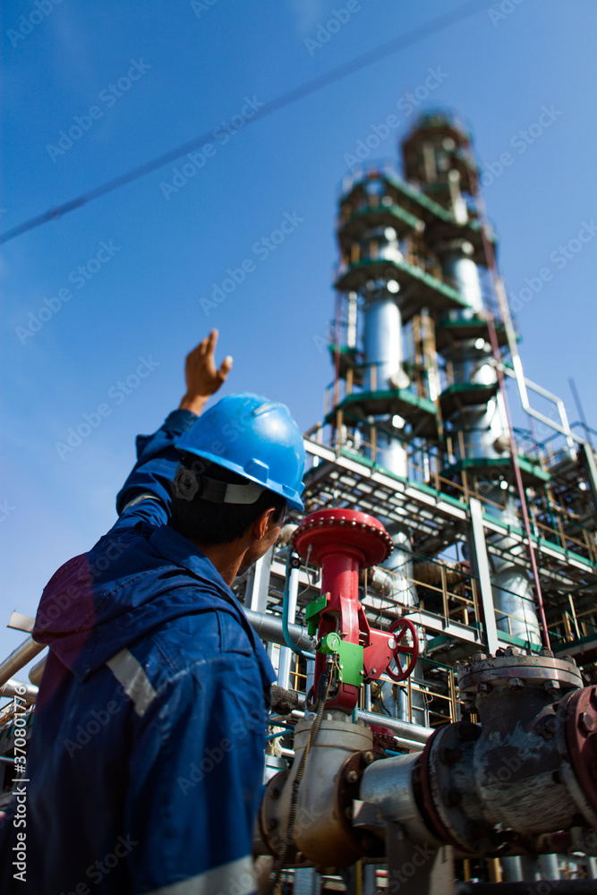 Oil refinery worker with one hand up. Blue work wear and helmet and ...