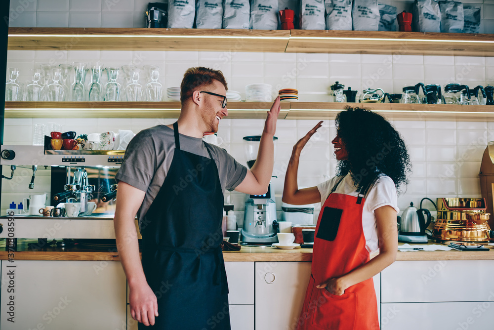 Cheerful caucasian barista giving five african american waitress for ...