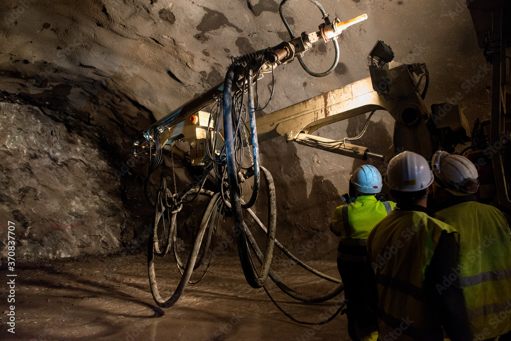 Back view of male engineers in uniform and helmets using drill ...