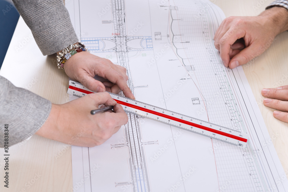 High angle side view of anonymous professional architects making marks ...