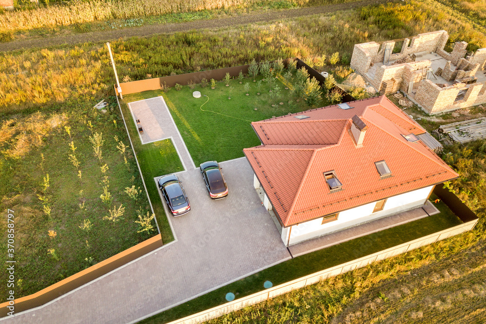 Top down aerial view of two private houses, one under construction with ...