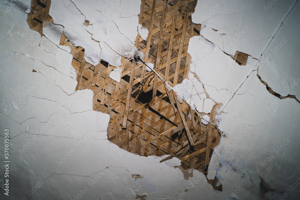 Dilapidated ceiling of an old house. damaged wall with a hole with ...