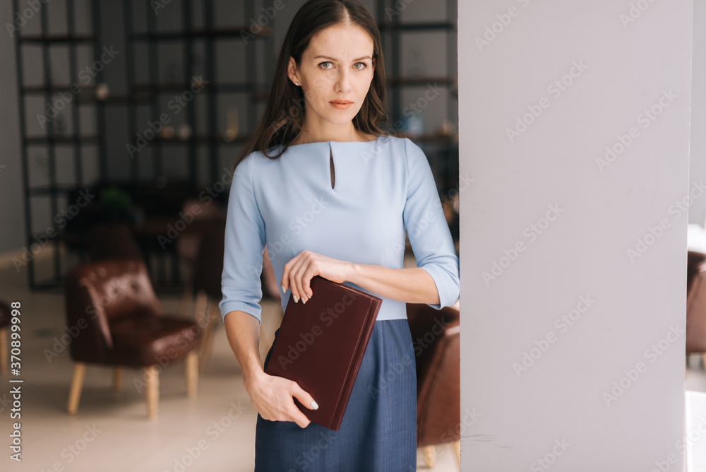 Professional young businesswoman holding file folder while standing ...