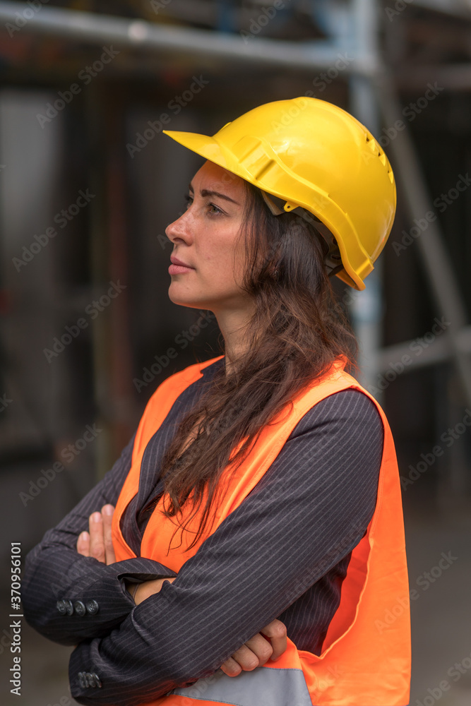 Portrait of a beautiful female factory worker wearing a protective ...