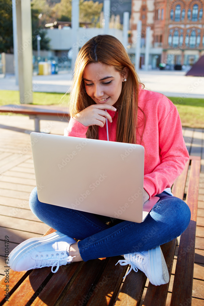 Portrait of gorgeous female student sitting with open laptop computer ...
