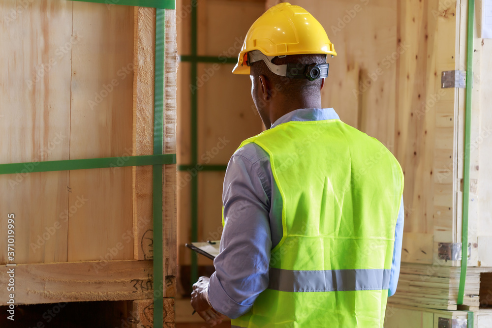 Back side of young black African worker wearing hardhat and safty vast ...