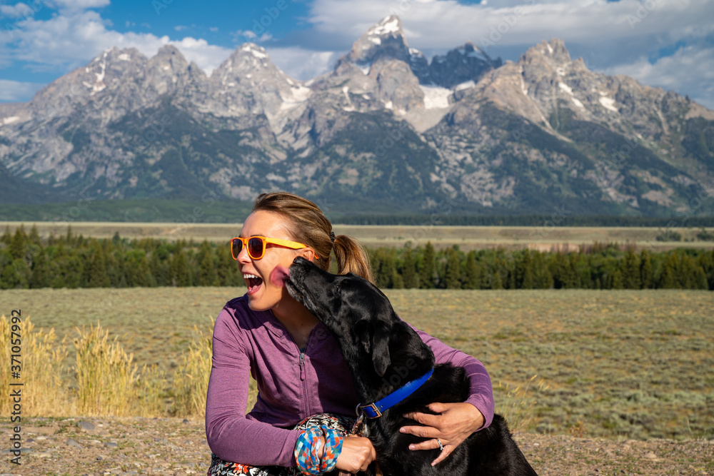 Woman hugs and holds her black labrador retriever dog in front of the ...