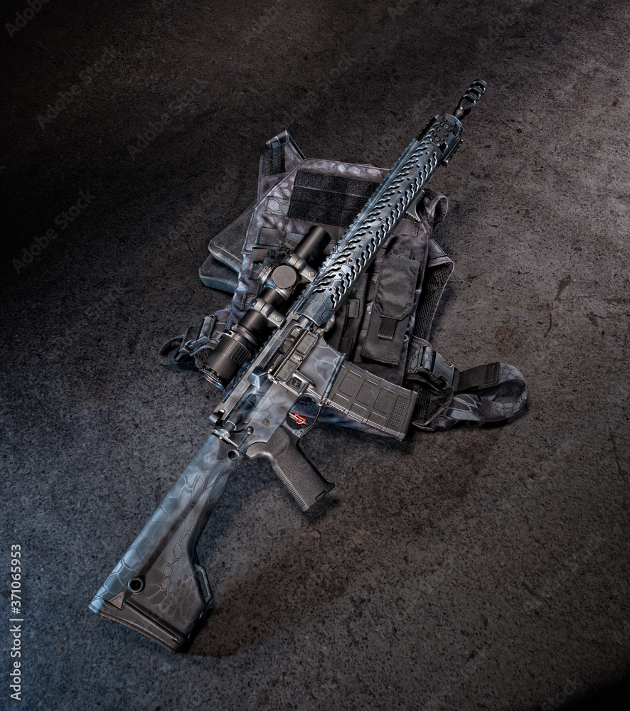 AR 15 style rifle with a magazine inserted, shot on a distressed floor ...