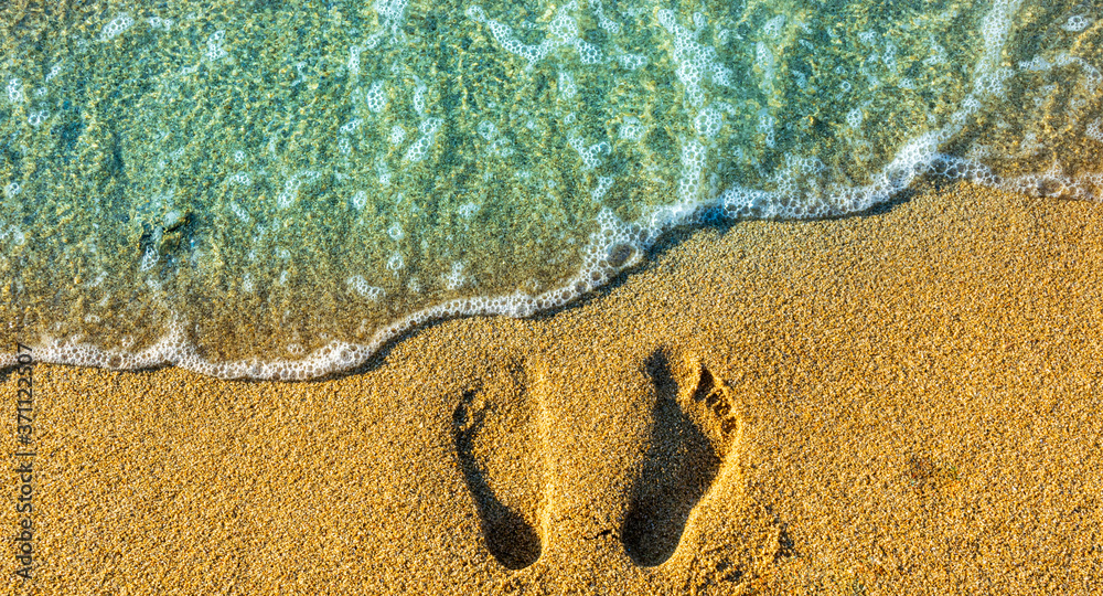 human footprints on sea beach golden sand with azure soft water ...
