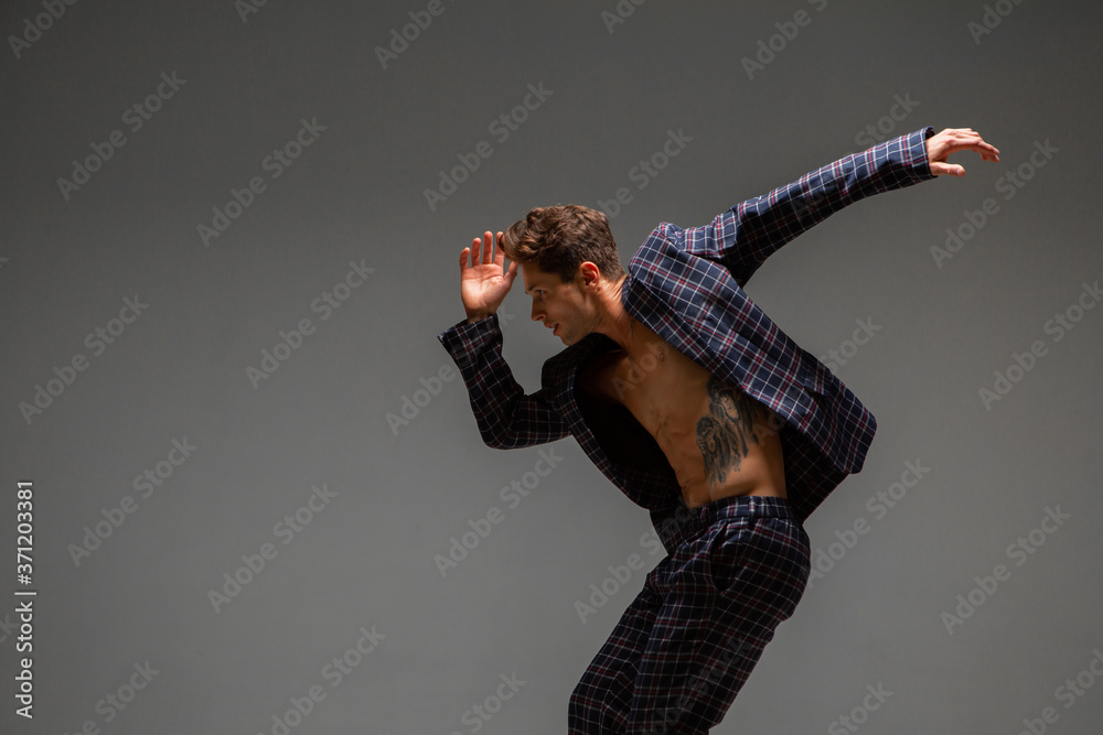 Cool young guy dancer in suit dancing modern expressive dance in studio ...