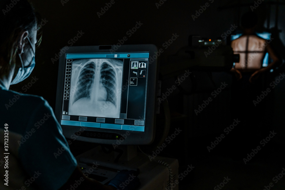 Man standing face against wall while doctor using X-Ray machine scan ...