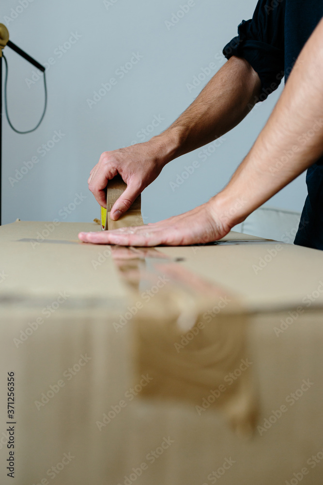 Young man closing a cardboard box with wrapping tape. Stock Photo ...