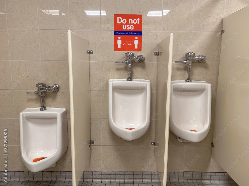 Urinals in a men's room. One urinal is unavailable due to COVID-19 ...