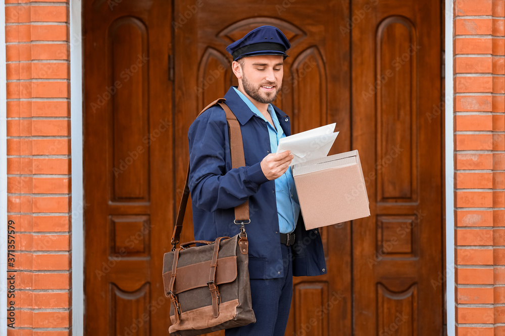 Handsome young postman with parcel and letters outdoors Stock Photo ...