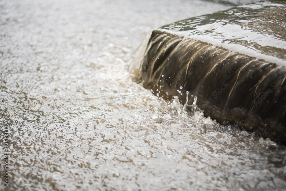 Foto de The stream of water flows down from the sidewalk. Heavy rain ...