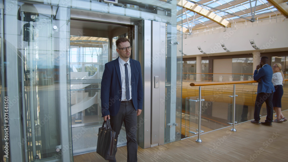 Tired overworked employee walking out of elevator and going home after ...