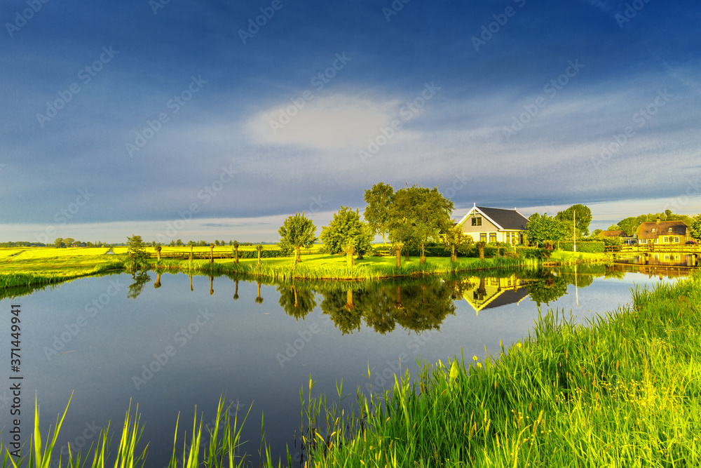 Beautiful Dutch polder landscape with channel a mansion and beautiful warm light of the rising ...