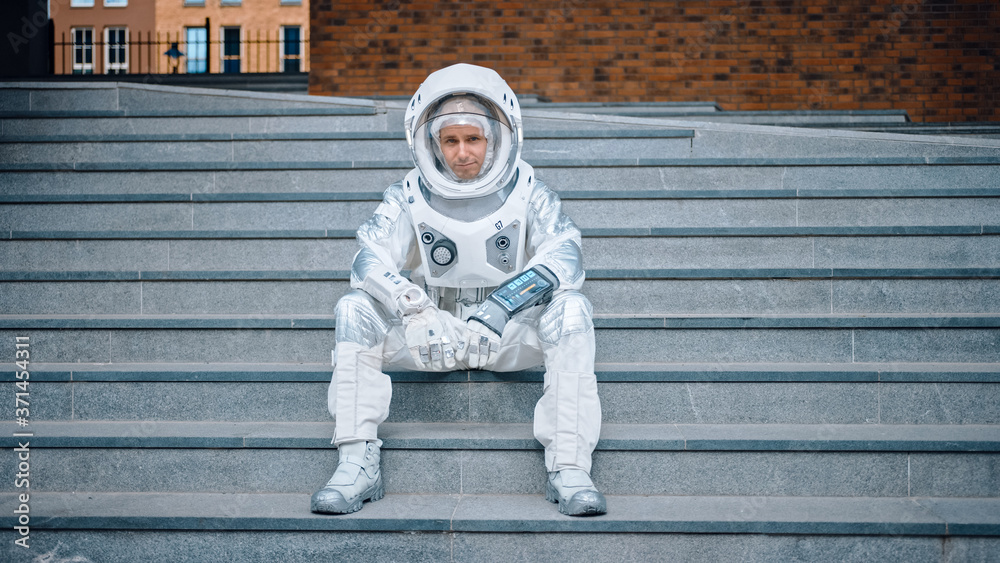 Sad Man in Spacesuit is Sitting on Concrete Stairs. Astronaut is ...