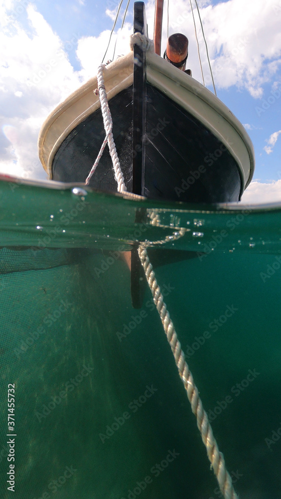Underwater split photo of traditional classic wooden fishing boat ...