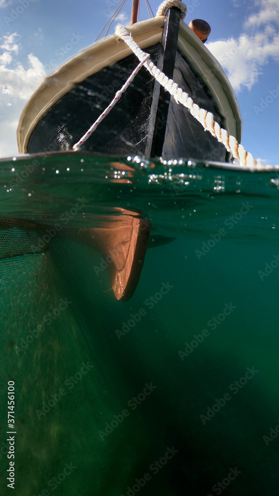 Underwater split photo of traditional classic wooden fishing boat ...