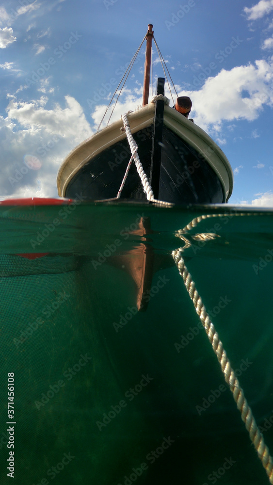 Underwater split photo of traditional classic wooden fishing boat ...