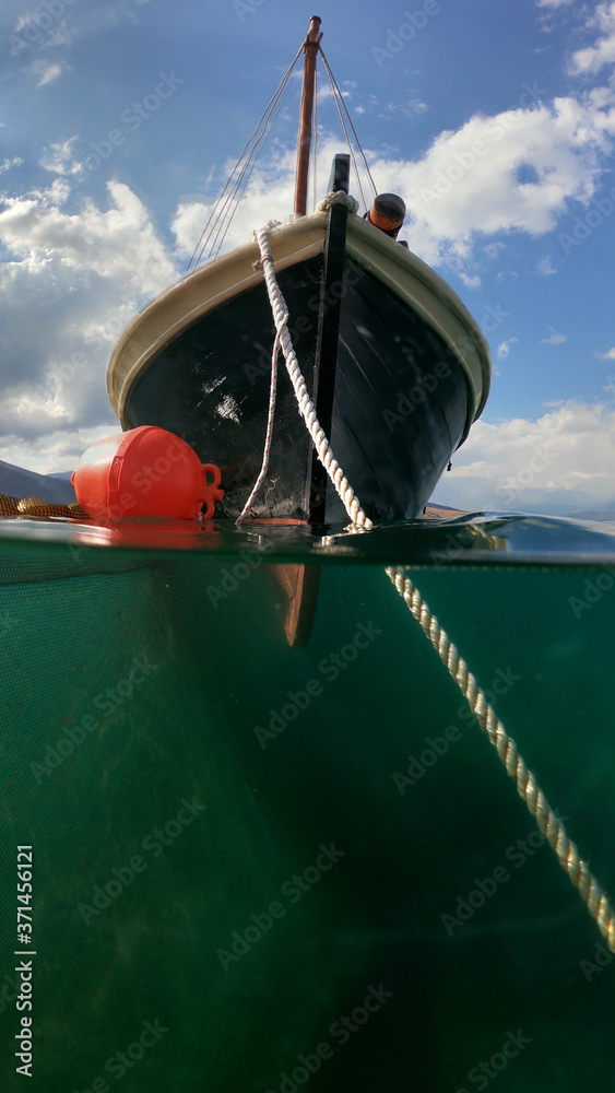 Underwater split photo of traditional classic wooden fishing boat ...