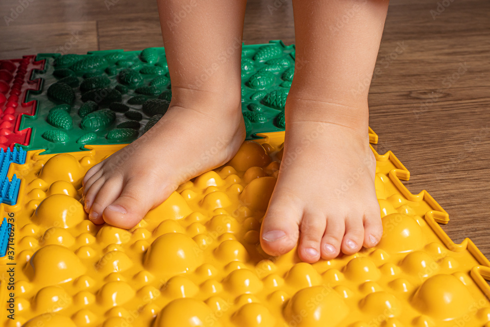 The legs of a small child on orthopedic mats. Bright surfaces for ...