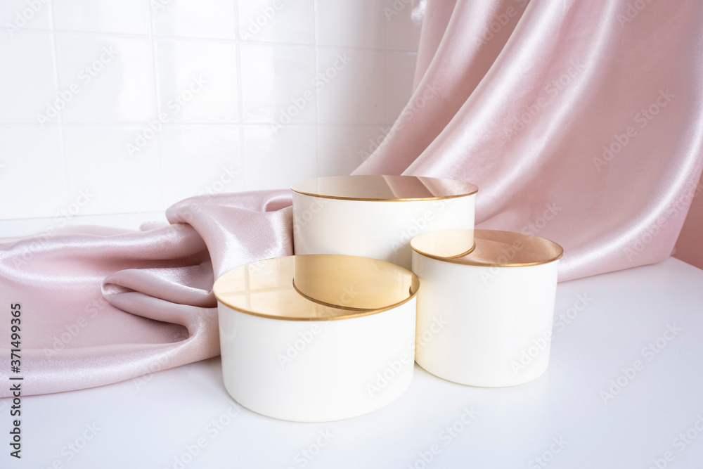 three beige podium topper with a gold top on a satin background with ...