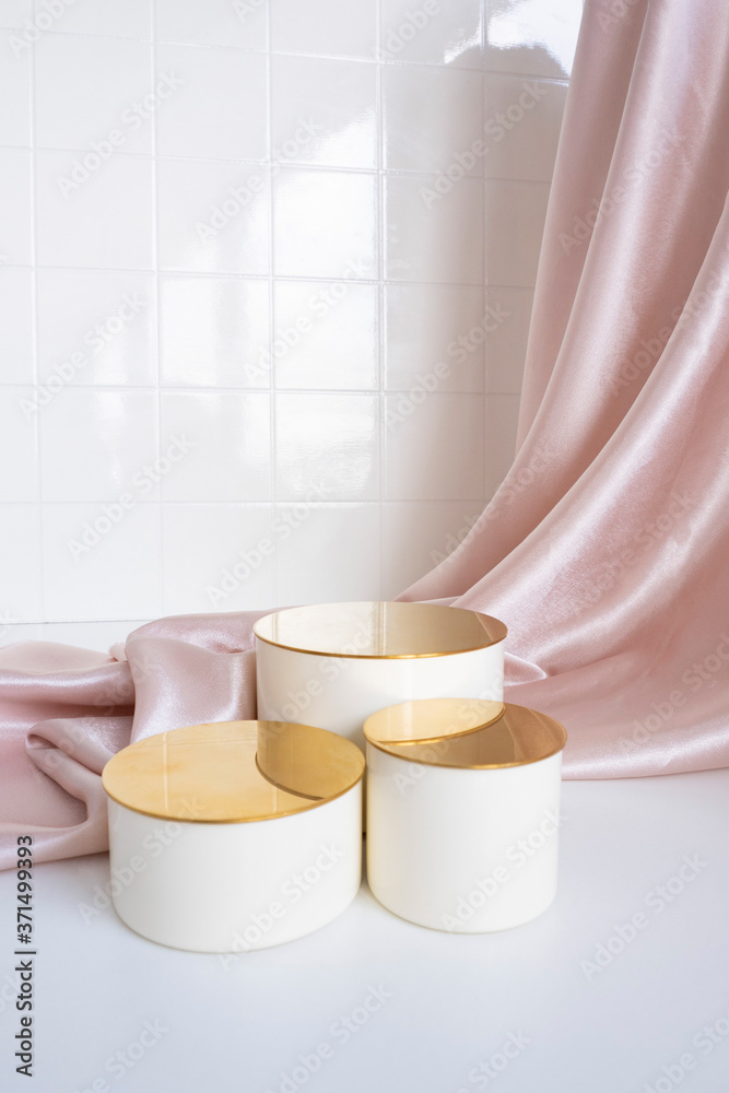 three beige podium topper with a gold top on a satin background with ...