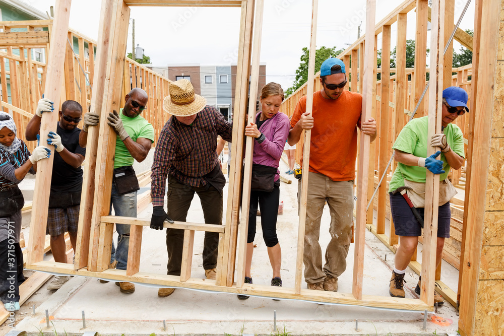 Volunteers lifting wall at construction site Stock Photo | Adobe Stock