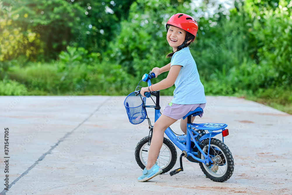 Happy child girl cycling in the park in the village for evening with ...