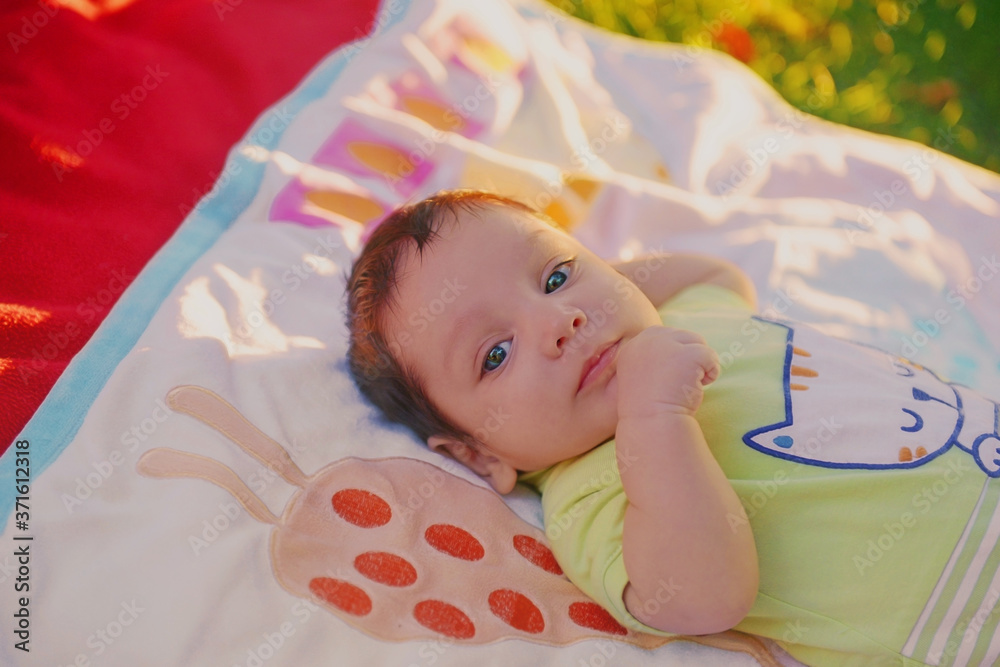 Bebé, bebe, acostado, con personalidad, en la manta sobre el césped ...
