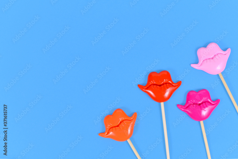 Red and pink plastic kiss mouth photo booth props on sticks on blue ...