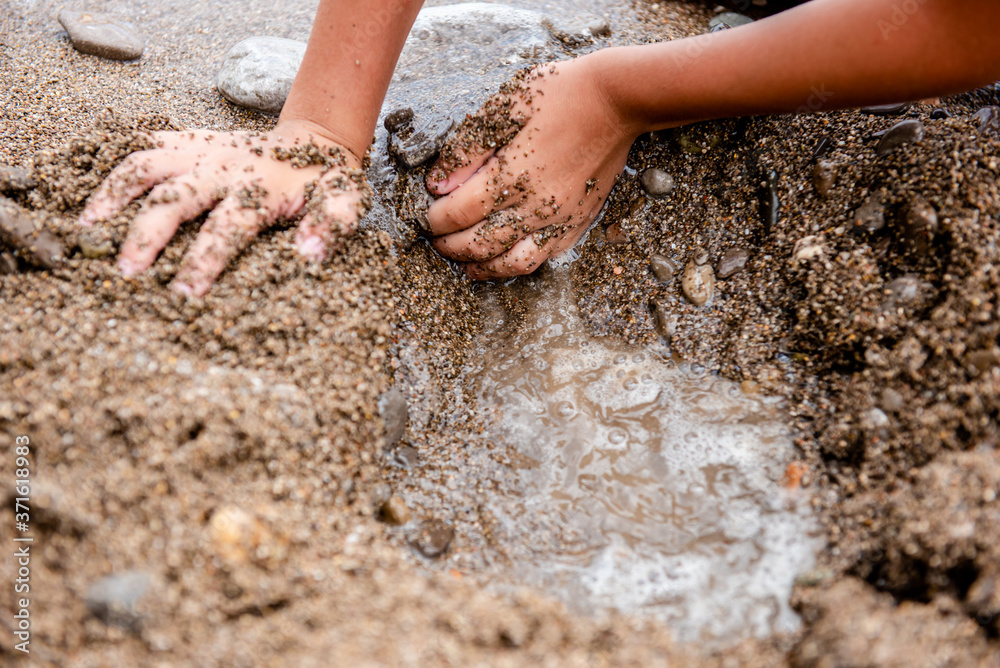 child plays on the beach in the sand. Children's hands in the sand on ...