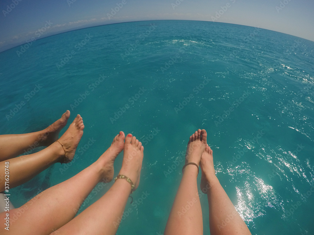 Three friends dangle their feet over the ocean at Fraser Island ...