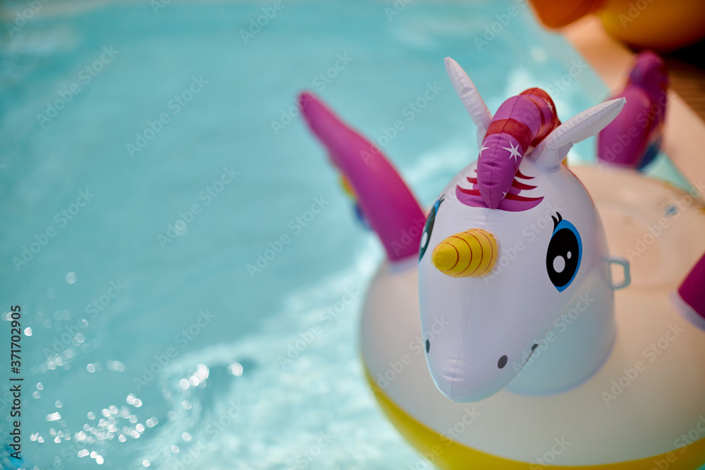 Inflatable colorful white unicorn at the swimming pool. Vacation time ...