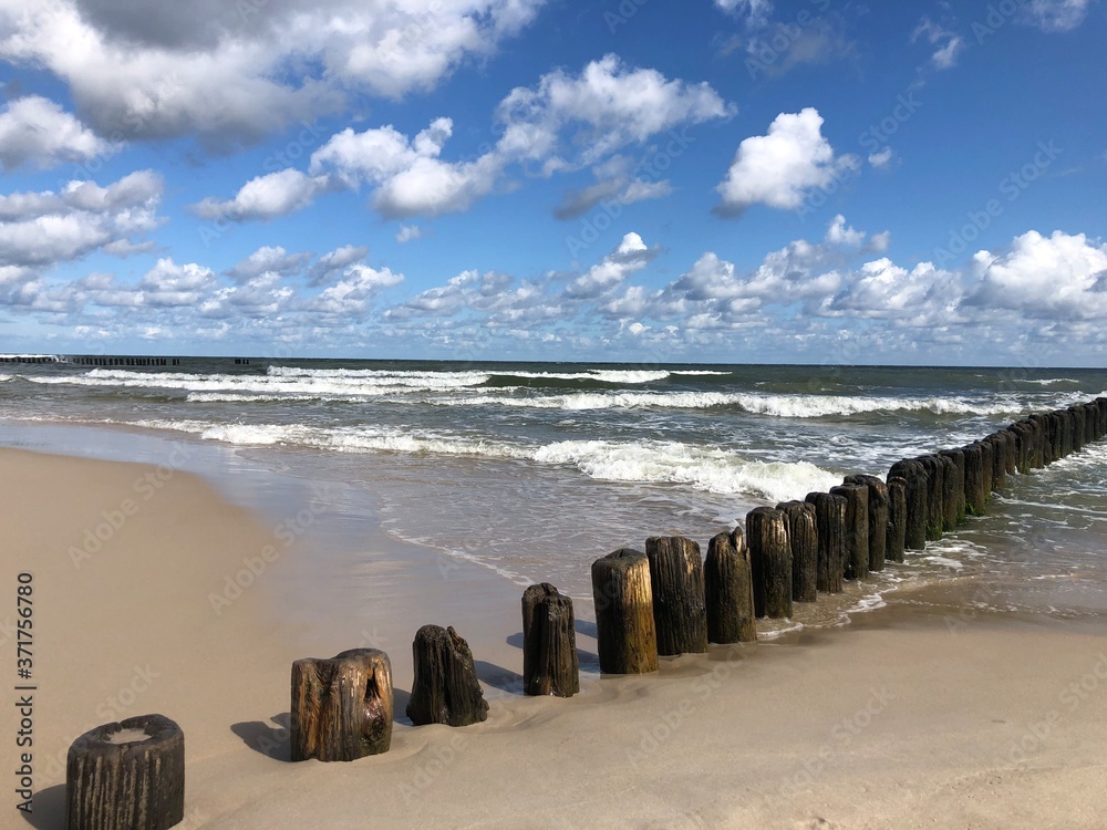 falochrony (drewniane pale, słupy) w morzu, pod błękitnym niebem, białe ...